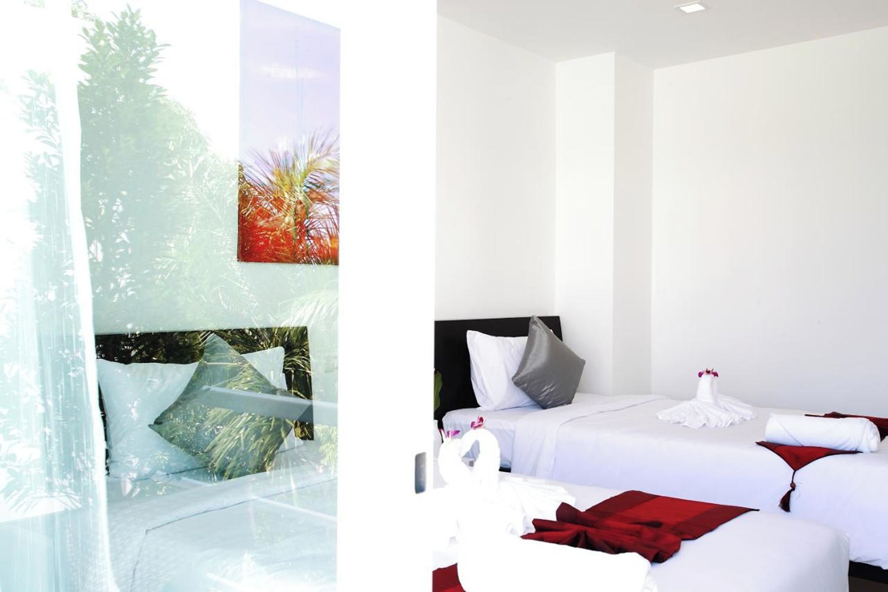 Quarto de hotel moderno com parede de vidro, cama com roupa de cama branca, cabeceira e uma pequena mesa com um objeto decorativo.