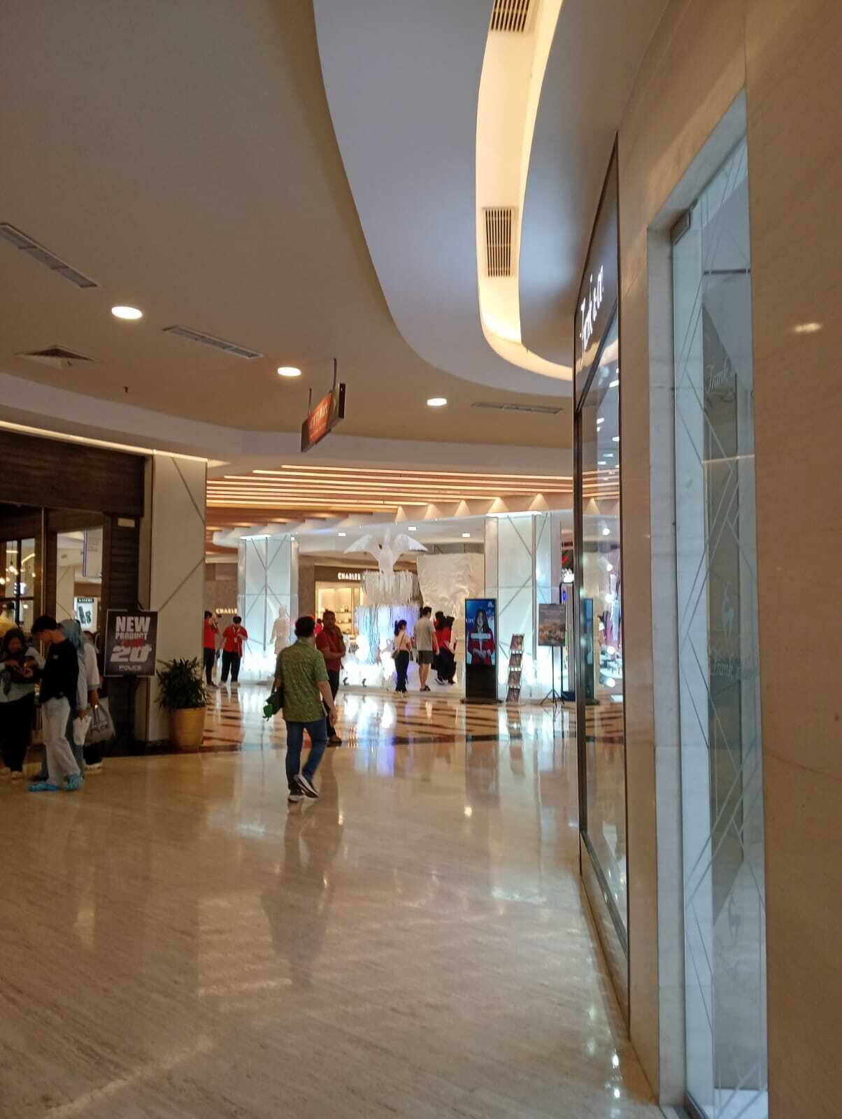 Interior espaçoso de um shopping moderno, com teto curvo, pisos lustrosos e diversas lojas.