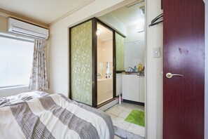 Quarto com cama, porta deslizante para um banheiro e vista para o banheiro.