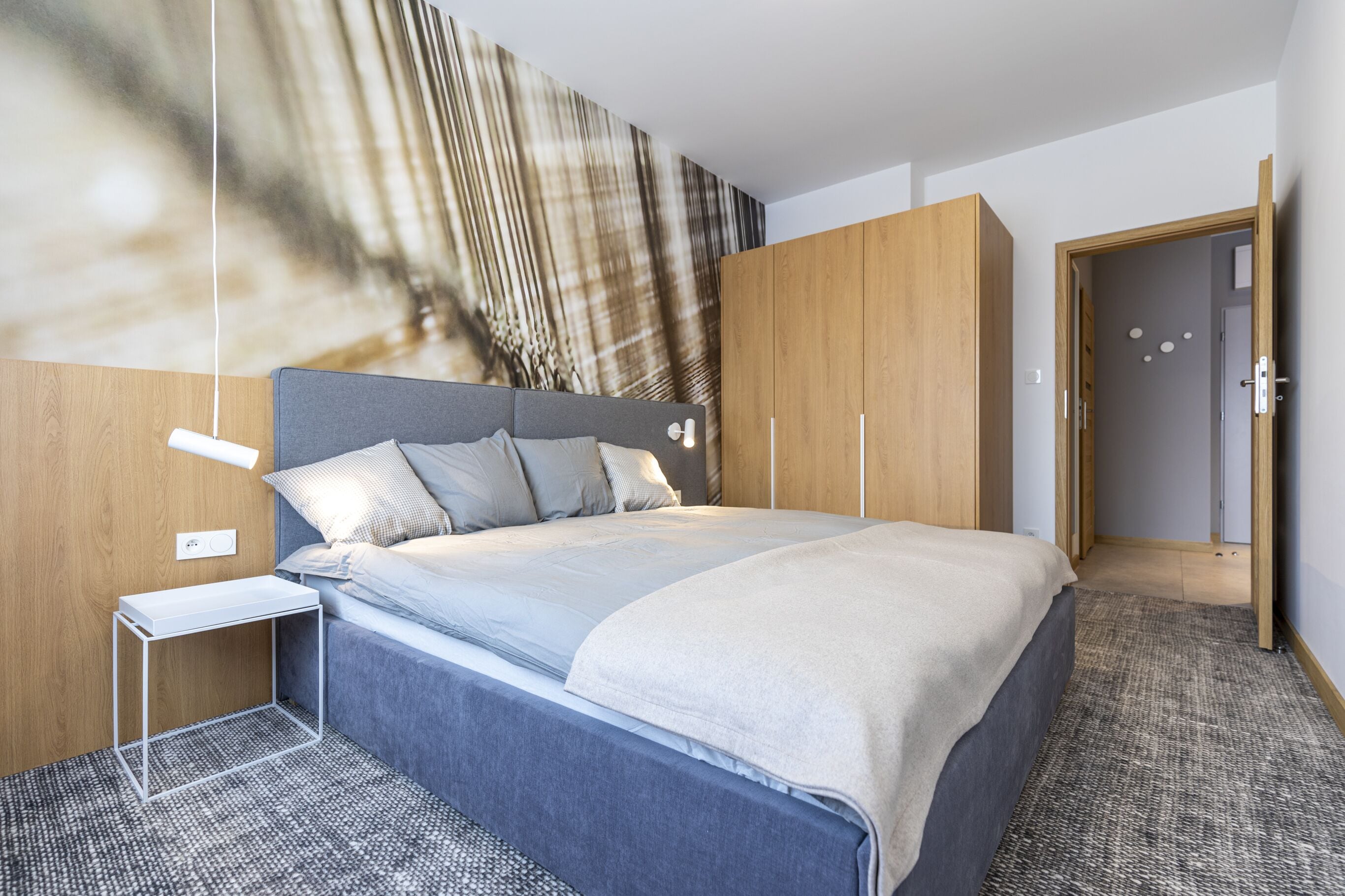 Quarto moderno com cama grande, mesa de cabeceira e guarda-roupa.