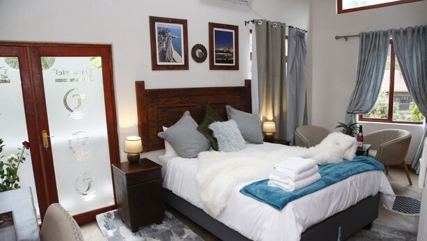 Quarto bem arrumado com cama, mesas de cabeceira, uma cadeira e uma janela com cortinas.
