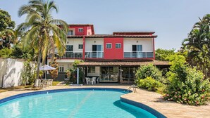 Um edifício de dois andares com piscina, área de estar externa e vegetação exuberante.