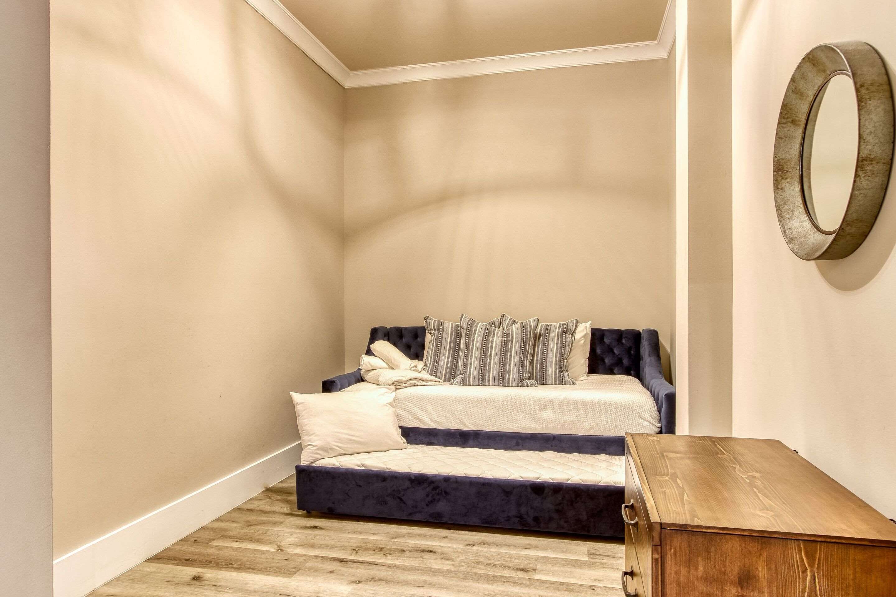 Um quarto com uma cama, uma cômoda de madeira e um espelho na parede.