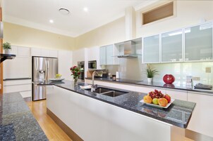 Cozinha moderna com ilha central, eletrodomésticos de aço inoxidável e uma janela grande.