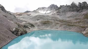 Paisagem montanhosa com um lago azul-turquesa límpido, rodeado por terreno rochoso.