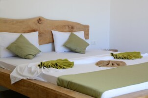 Cama com cabeceira de madeira, duas almofadas e duas toalhas verdes.
