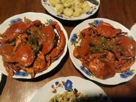 Duas travessas de caranguejo cozido com legumes sobre uma mesa de madeira.
