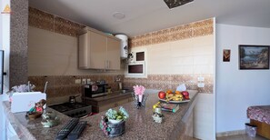 Cozinha com micro-ondas, fogão, pia e objetos decorativos no balcão.