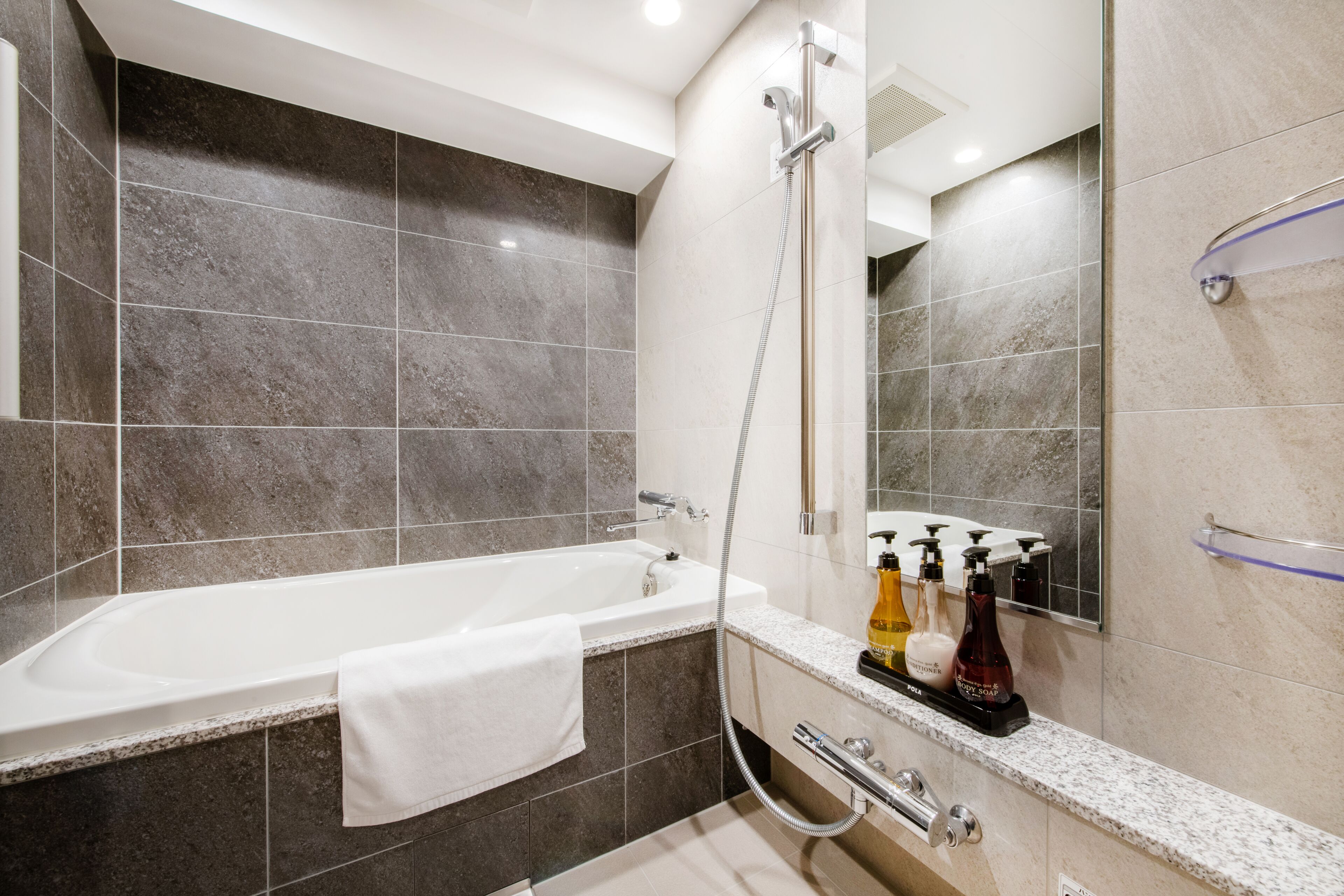 Casa de banho moderna com banheira, chuveiro e lavatório com produtos de higiene pessoal.