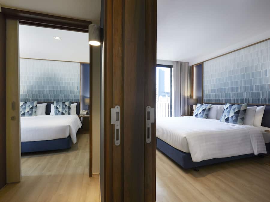 Quarto de hotel com duas camas, uma janela grande e vista para a cidade.