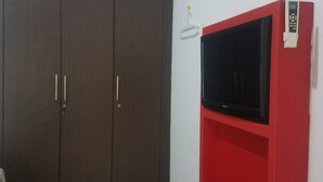 Quarto com guarda-roupa, um suporte de TV vermelho e parede branca.