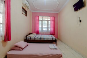 Quarto com cama, mesa de cabeceira, televisão e janela com cortinas.
