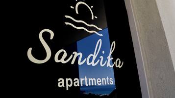 Placa para os apartamentos Sandiko, com ilustração de sol e ondas.
