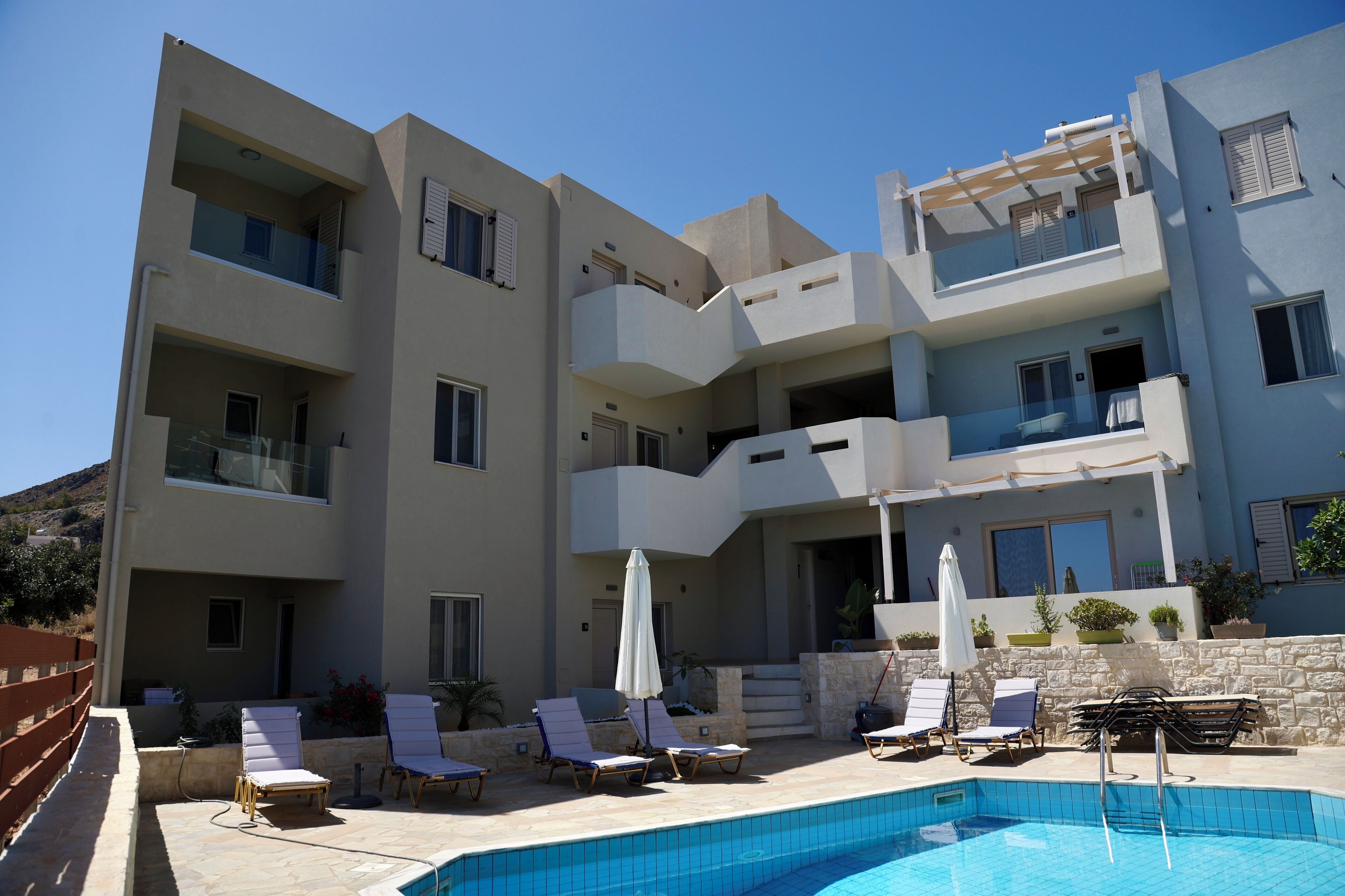Um edifício moderno de vários andares com piscina, área de estar ao ar livre e varandas.