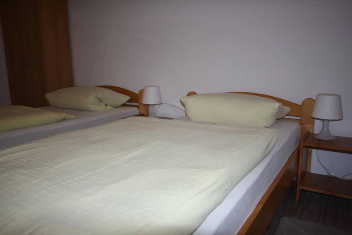 Uma cama de solteiro com cabeceira de madeira e duas mesas de cabeceira, cada uma com uma luminária.