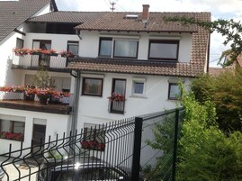 Um edifício de dois andares com varandas decoradas com floreiras.