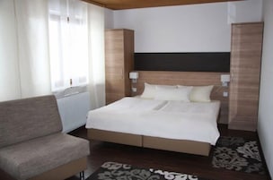 Quarto com cama, sofá, guarda-roupa e janela com cortinas.