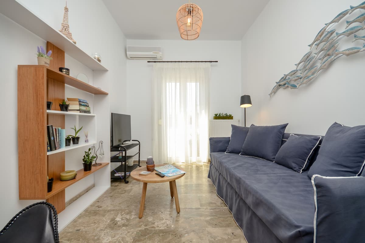Uma sala de estar moderna com um sofá, uma mesa de centro e uma estante de livros.