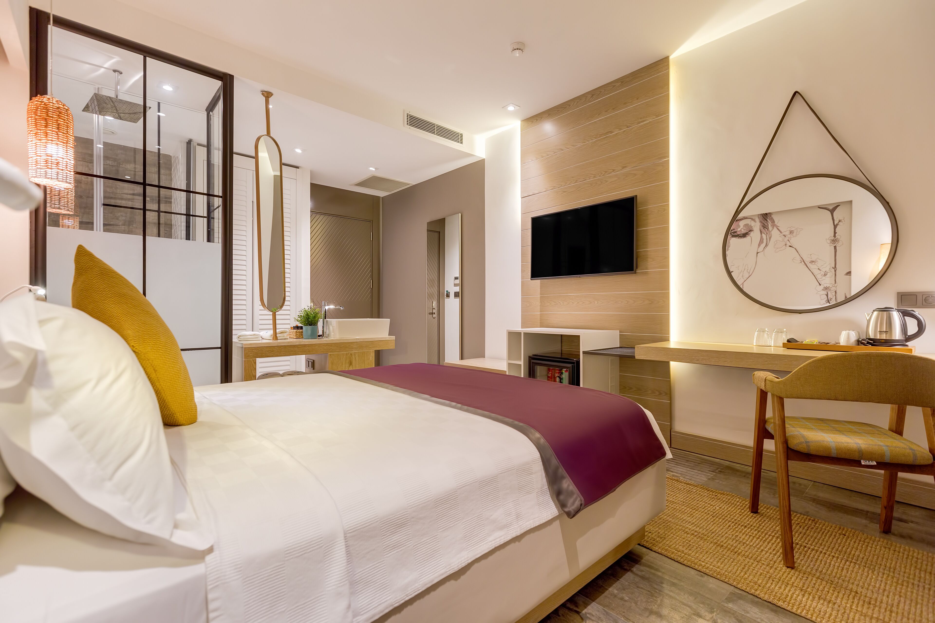 Quarto de hotel moderno com uma cama grande, uma escrivaninha, uma cadeira, uma TV e um espelho.