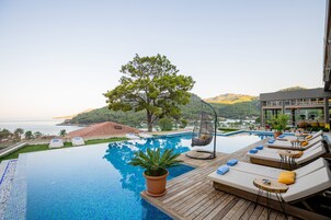 Área de piscina com espreguiçadeiras, cadeira suspensa e planta em vaso.