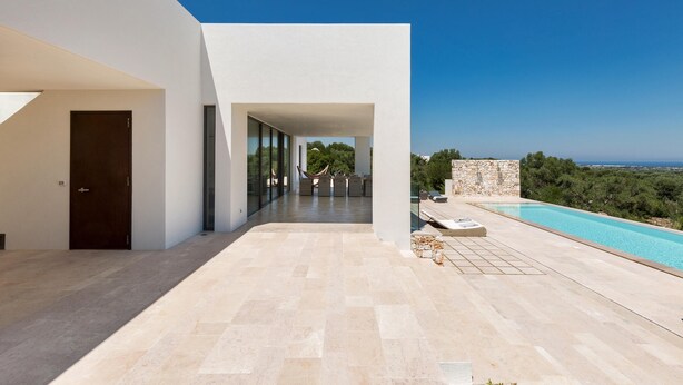 Uma casa moderna com piscina, um alpendre e vista para o mar.