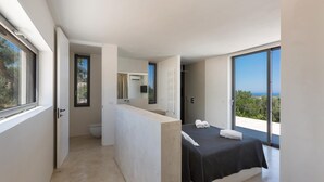 Quarto moderno com cama grande, banheiro e varanda com vista.