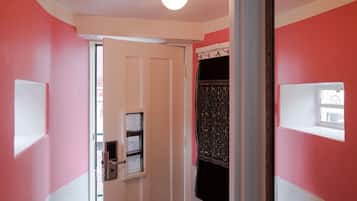 Um corredor com paredes cor-de-rosa, uma porta branca e uma janela com cortina.