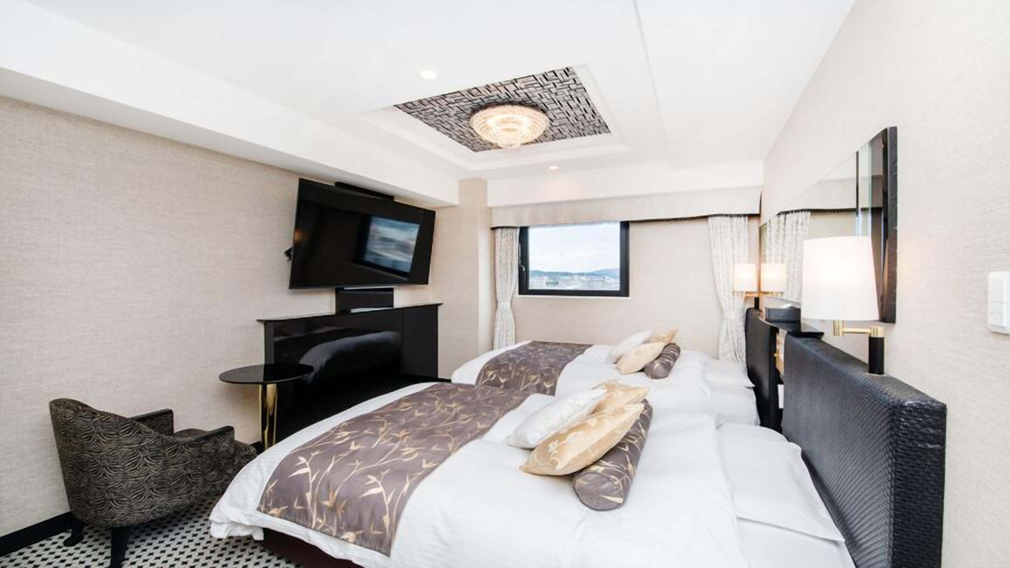 Quarto de hotel com cama, televisão, escrivaninha e janela.
