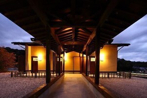 Uma galeria coberta que leva a um edifício com estilo arquitetônico tradicional, pilares de madeira e iluminação acolhedora.
