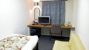Quarto de hotel com uma cama, uma mesa com computador, uma cadeira e um sofá.