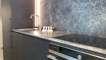 Cozinha moderna com painel de mármore escuro, eletrodomésticos de aço inoxidável e forno embutido.