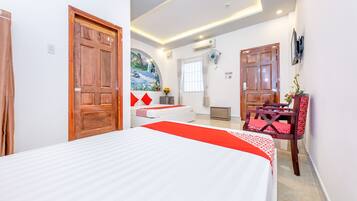 Quarto de hotel com cama, escrivaninha, cadeira, janela e porta.