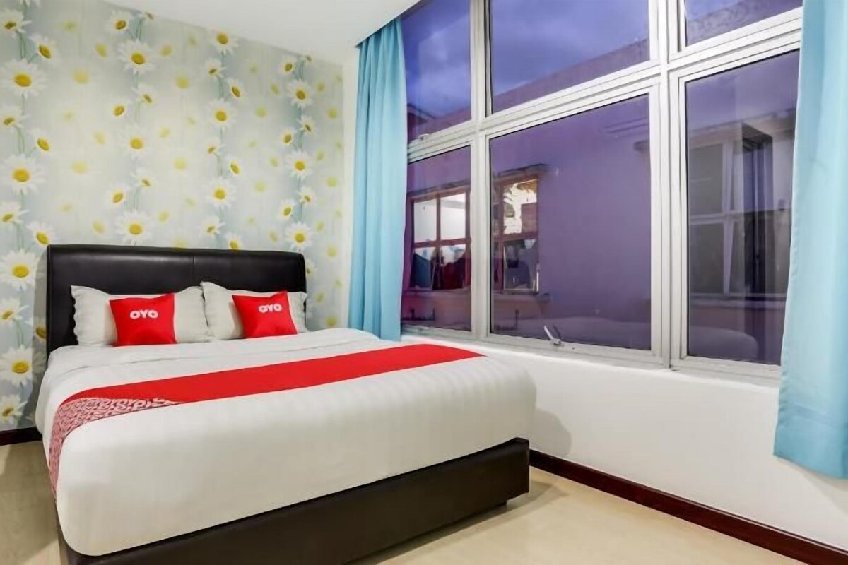 Quarto com cama, janela com cortinas e papel de parede com padrão de margaridas.