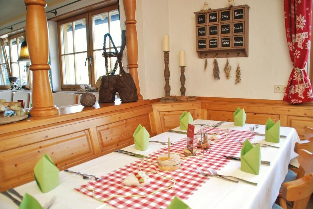 Uma sala de jantar com toalha xadrez, cadeiras de madeira e um quadro de menu na parede.
