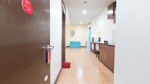 Um hall de hotel com balcão de recepção, sofá e porta com sinal de garantia de serviço.
