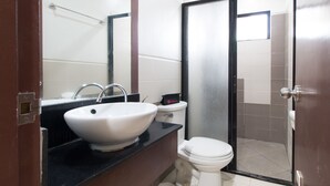 Casa de banho com lavatório branco, sanita e zona de duche.