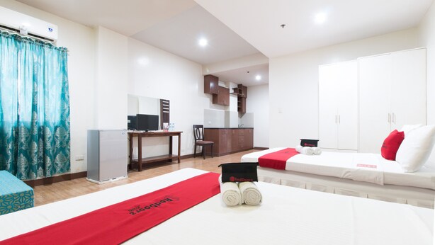 Quarto de hotel com uma cama, uma mesa de escritório com um computador, uma cadeira, um guarda-roupa e uma kitchenette.