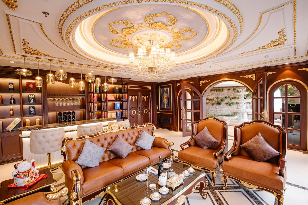 Um quarto luxuoso com área de bar, móveis elegantes e detalhes ornamentados no teto.