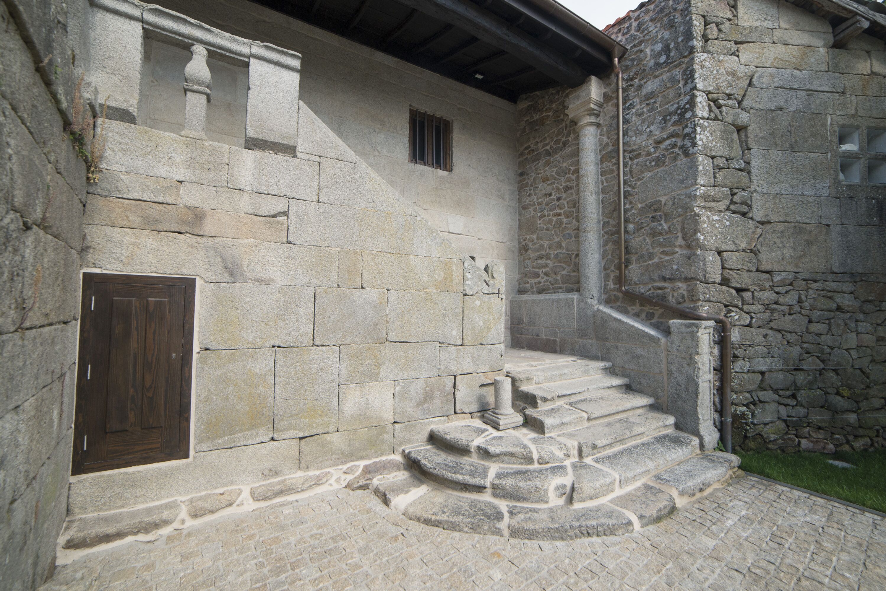 Um edifício de pedra com porta de madeira e um conjunto de degraus de pedra que levam à porta.