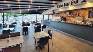 Um restaurante com área externa, um bar e vista para a piscina.