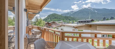 Um deck de madeira com área de estar externa e vista para montanhas.