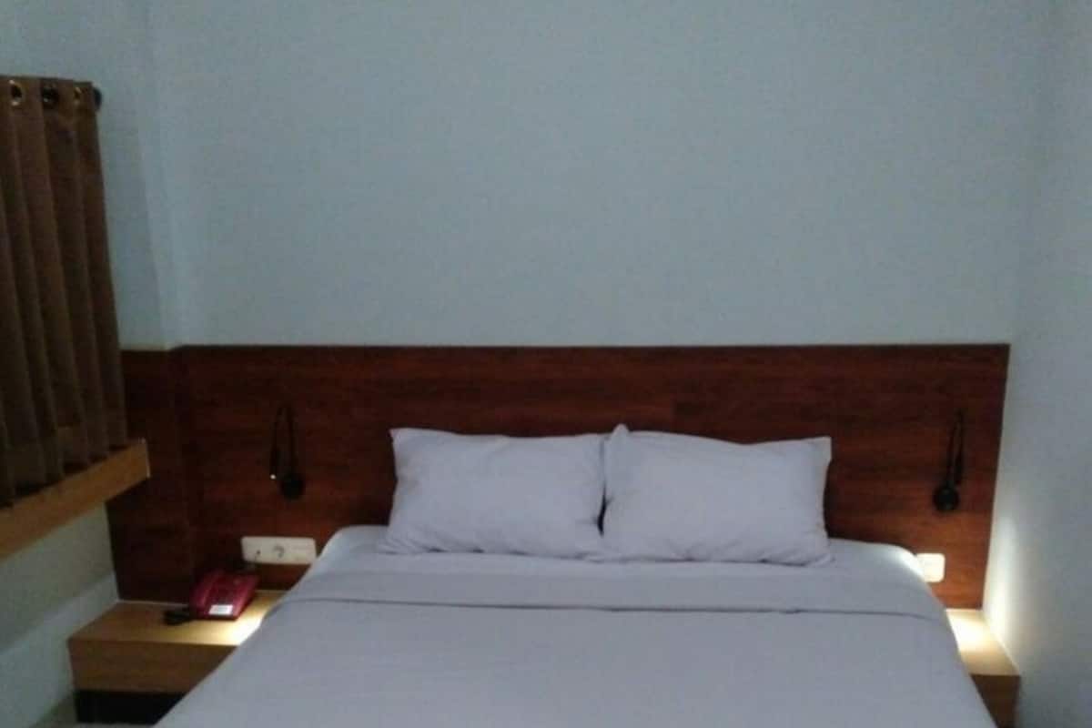 Cama bem arrumada com lençóis brancos, cabeceira de madeira e mesas de cabeceira com abajures.