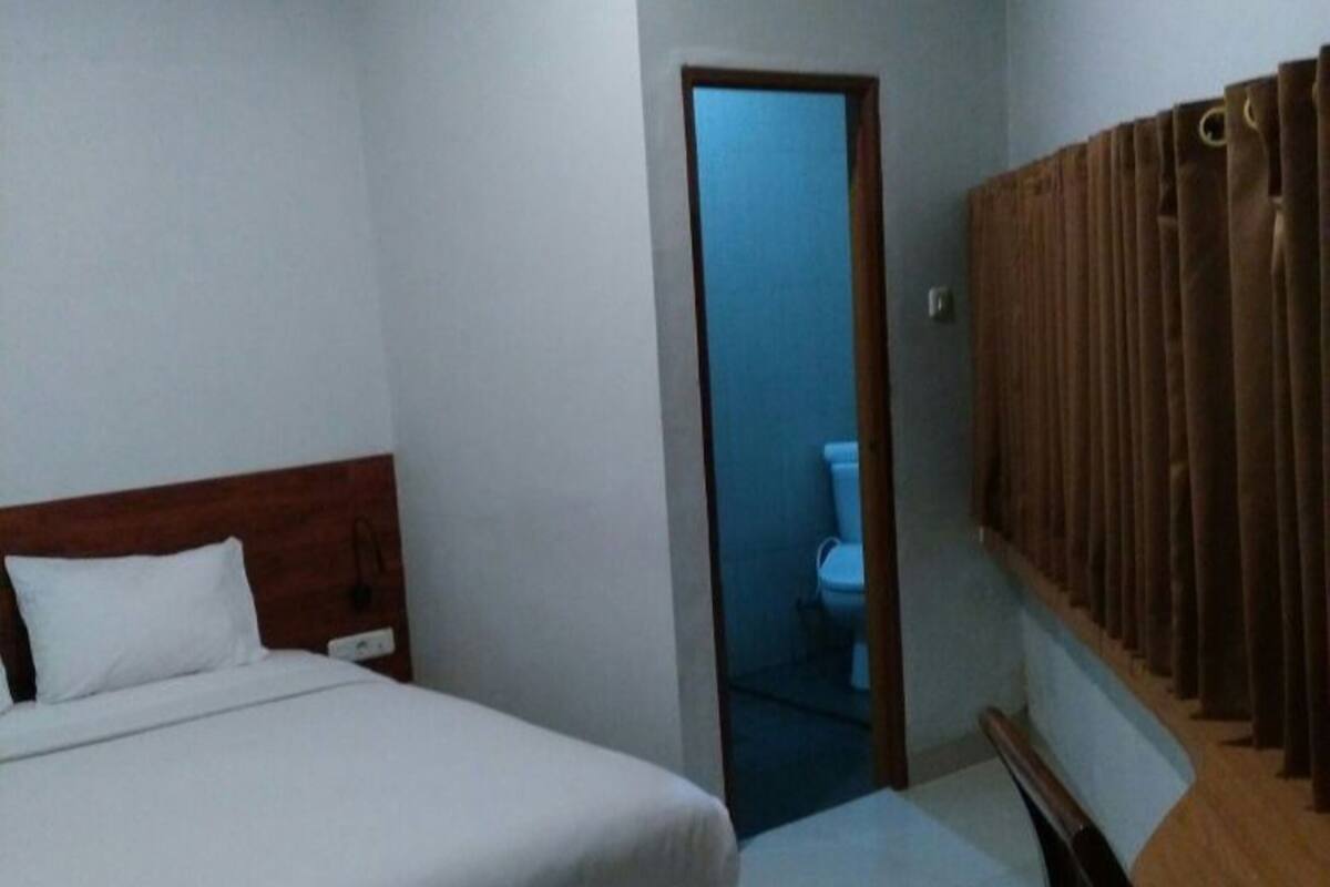 Quarto de hotel com cama, cabeceira de madeira, mesa de cabeceira e parede revestida de madeira.
