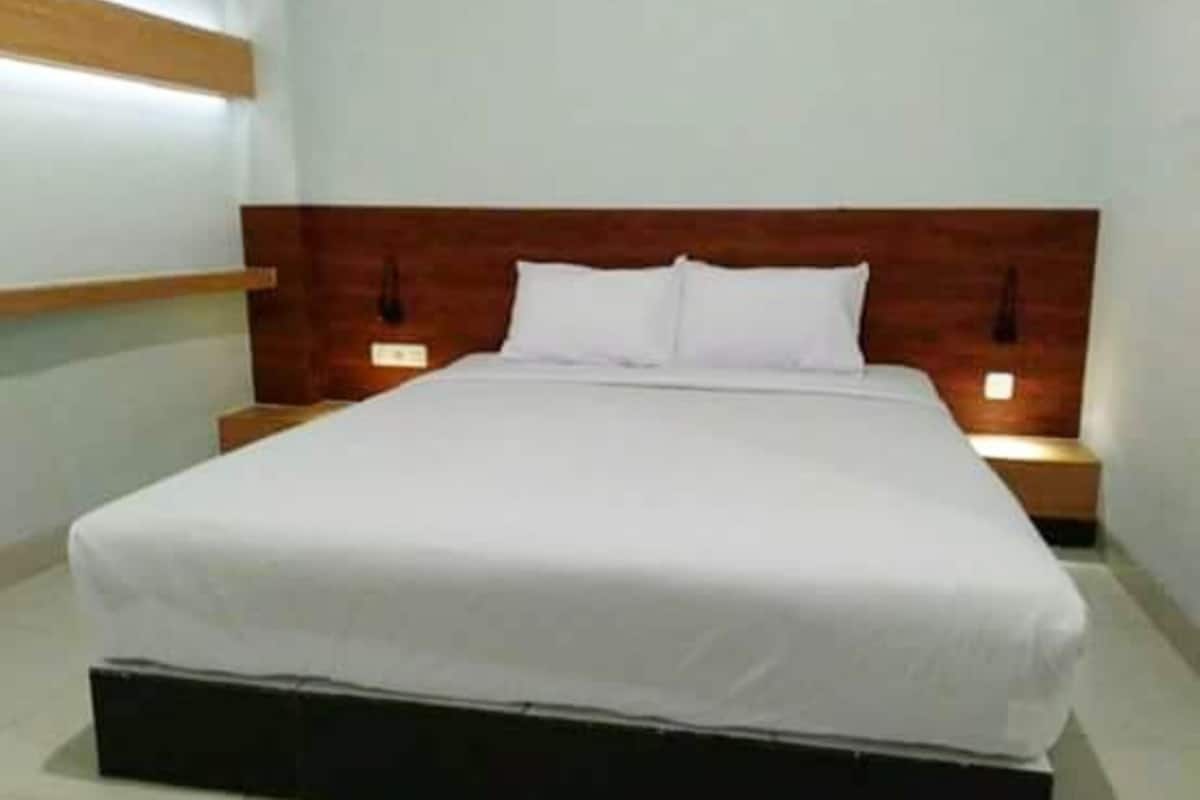 Cama bem arrumada com lençóis brancos em quarto de hotel.