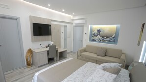 Quarto de hotel moderno com cama, escrivaninha, sofá e um quadro grande na parede.