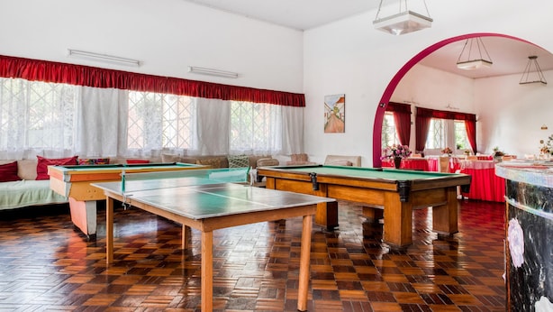 Uma sala de bilhar com várias mesas, um sofá e uma mesa de sinuca.