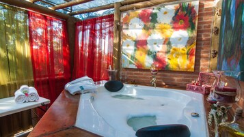 Um quarto de spa com uma banheira grande, cortinas vermelhas, um banco de madeira e uma pintura na parede.
