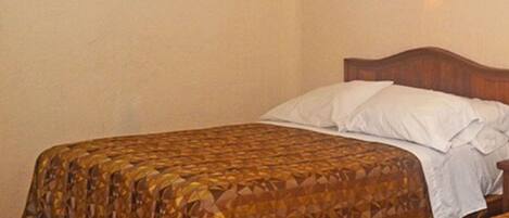 Quarto com duas camas, cada uma com roupa de cama estampada, luminária fixada na parede e um quadro na parede.
