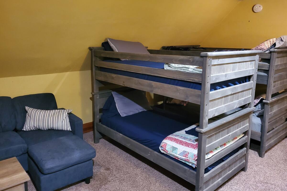 Um quarto com beliches, um sofá e uma mesinha.