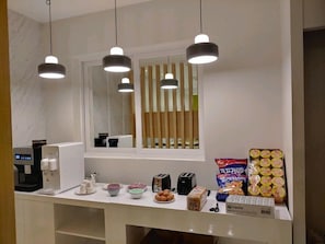 Uma cozinha moderna com cafeteira, torradeira e diversos alimentos sobre o balcão.